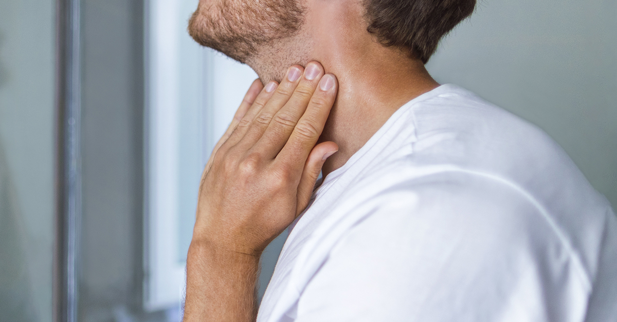 Thyroid self-exam checkup. Young man touching his neck at home bathroom ...